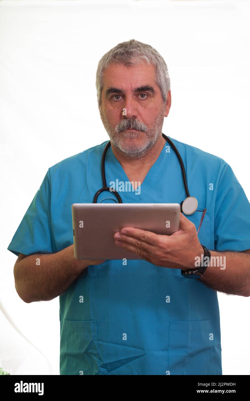 Senior doctor looking at camera with tablet in hand checking patient ...