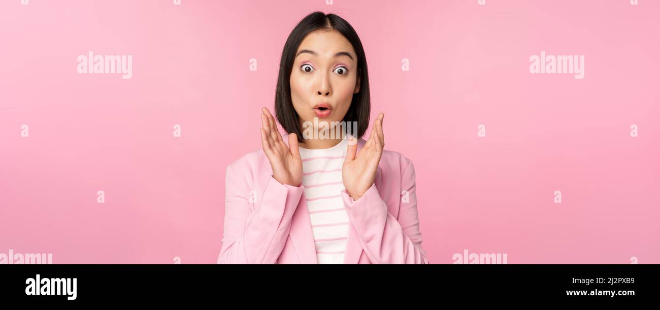 Portrait of asian businesswoman looking surprised at camera, clapping ...