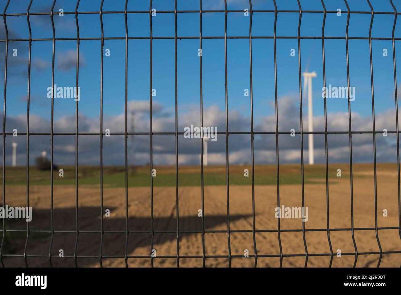 rural landscape with field and wind turbines behind metal fence Stock ...