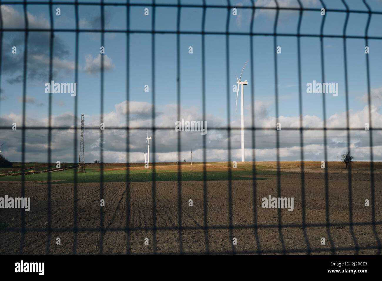 rural landscape with field and wind turbines behind metal fence Stock ...