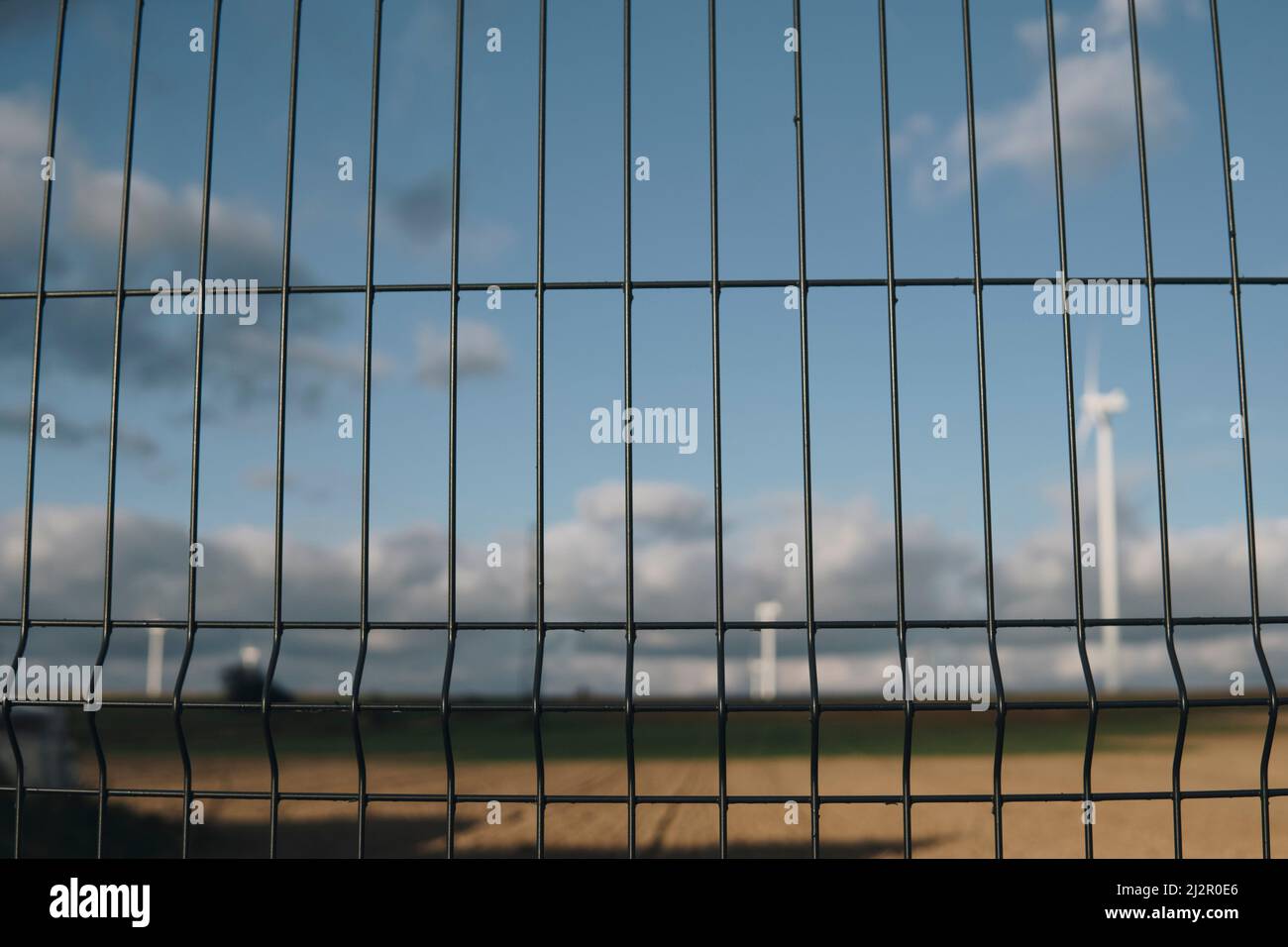 rural landscape with field and wind turbines behind metal fence Stock ...