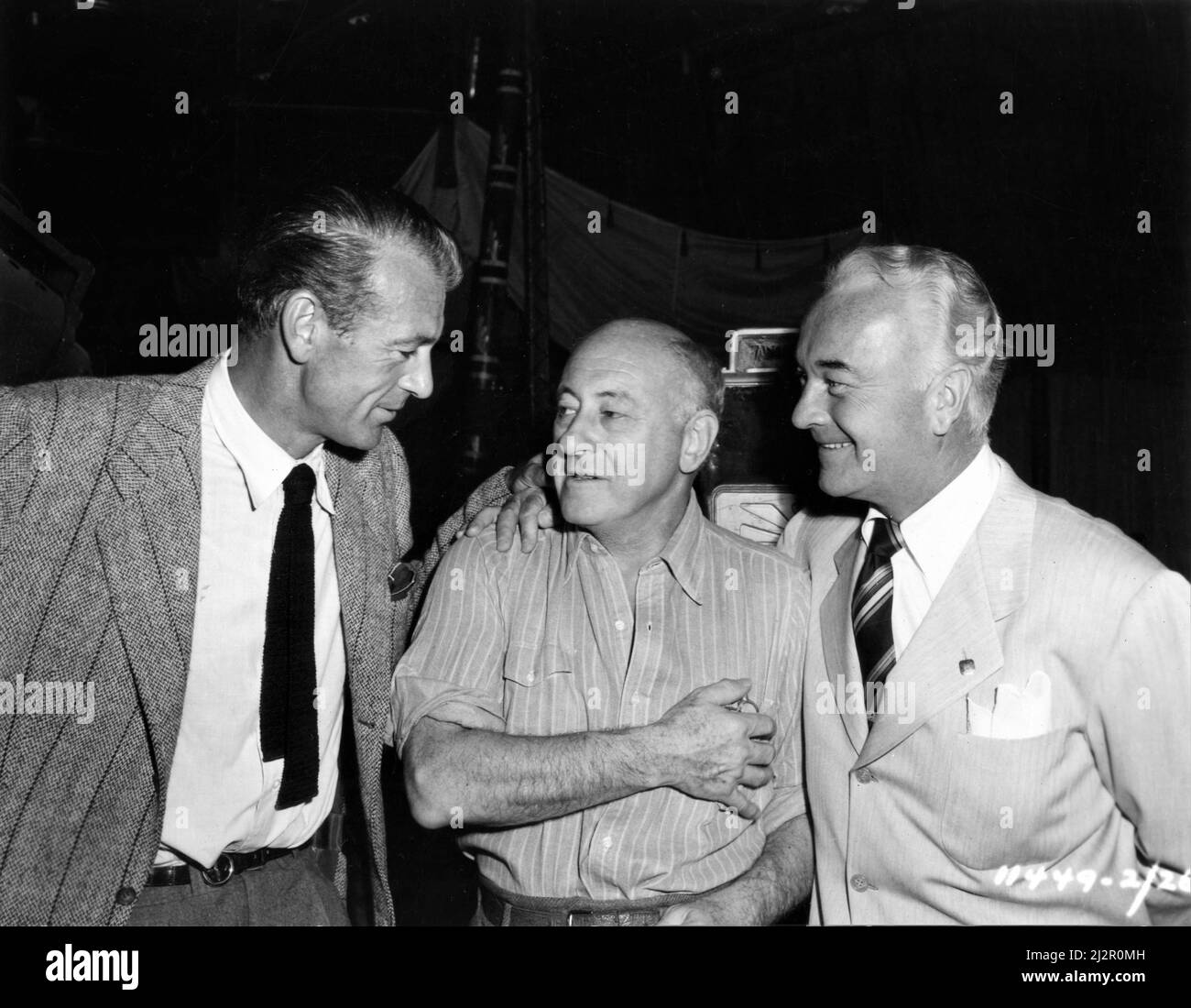 CECIL B. DeMILLE (centre) on set candid with Set Visitors GARY COOPER ...