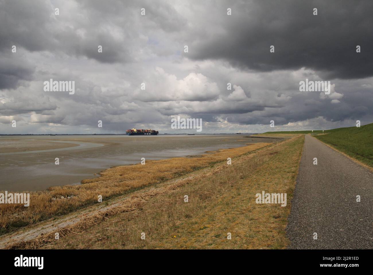 dutch coast landscape with cargo ship navigates along a colourful salt ...