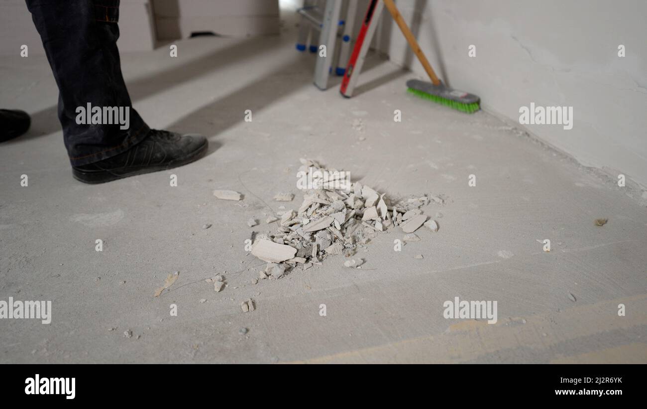 A worker removes construction debris with a brush. A man cleans up ...
