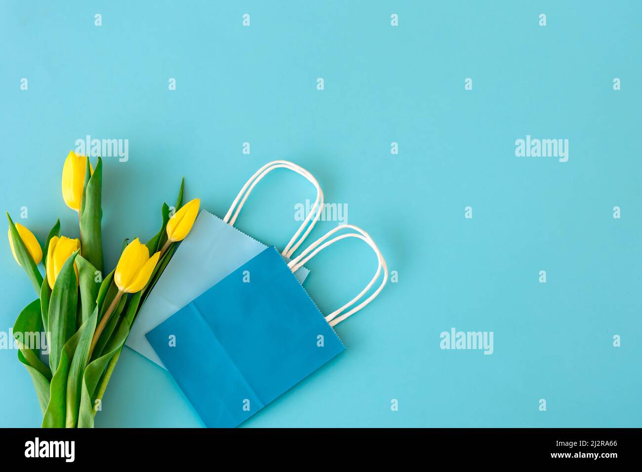 Flat lay blue background with flowers and paper bags Stock Photo - Alamy