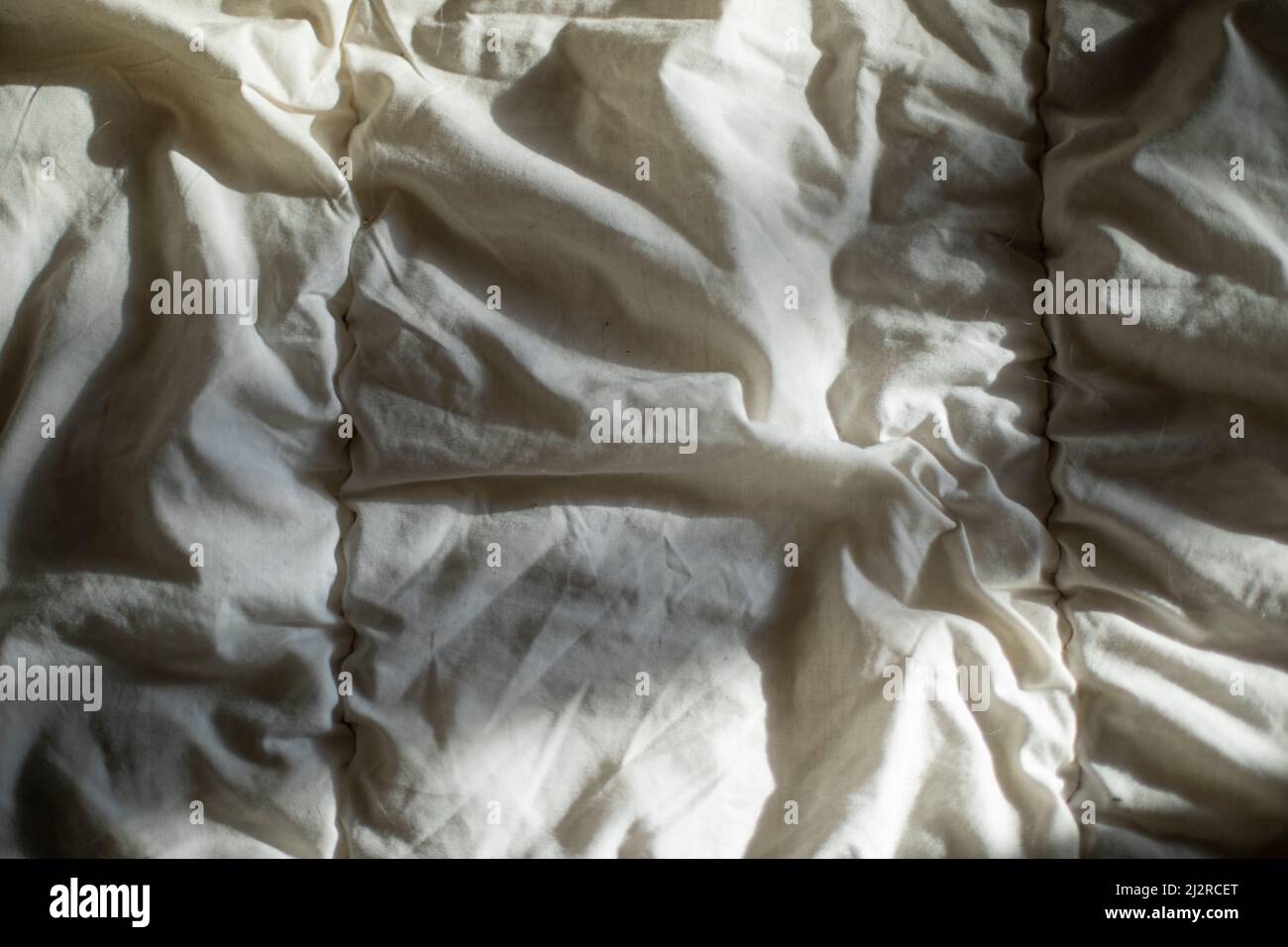 Matting sheet on bed. Texture of fabric in sunlight. Folds on bed linen ...