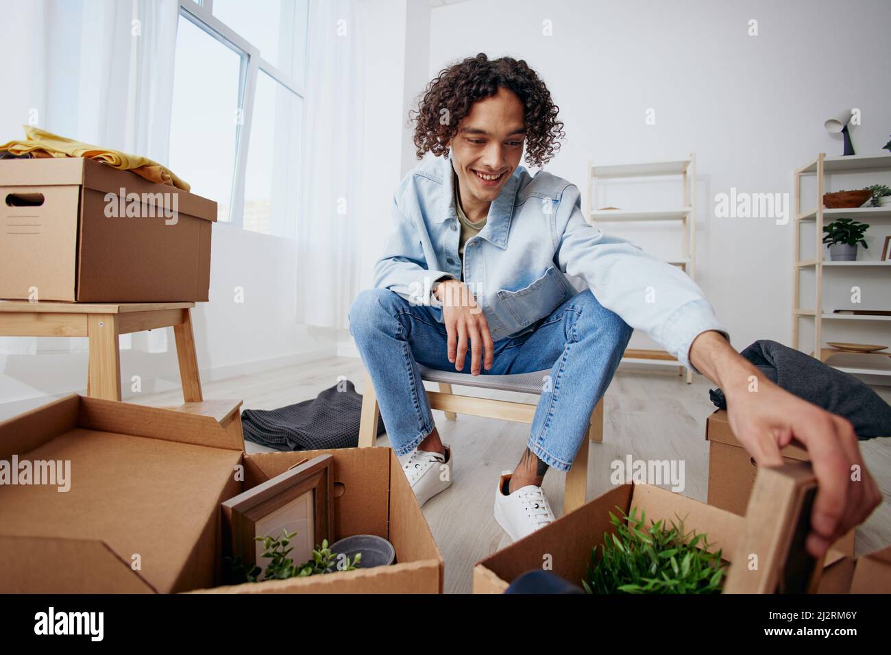guy with curly hair unpacking things from boxes in the room Lifestyle ...
