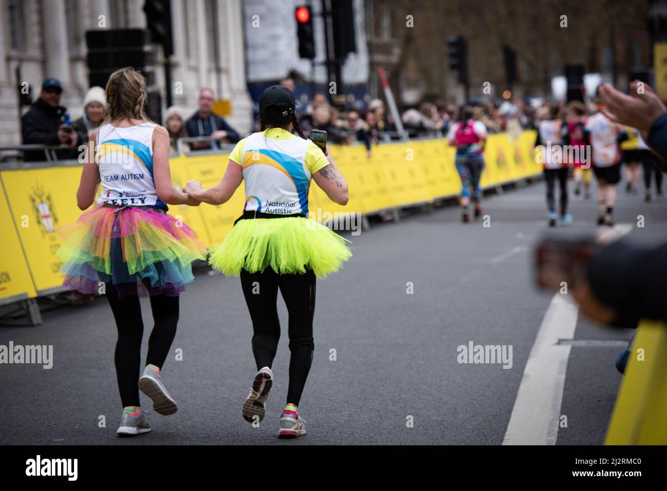 Runners dressed in tutus approach the finish line during the London ...