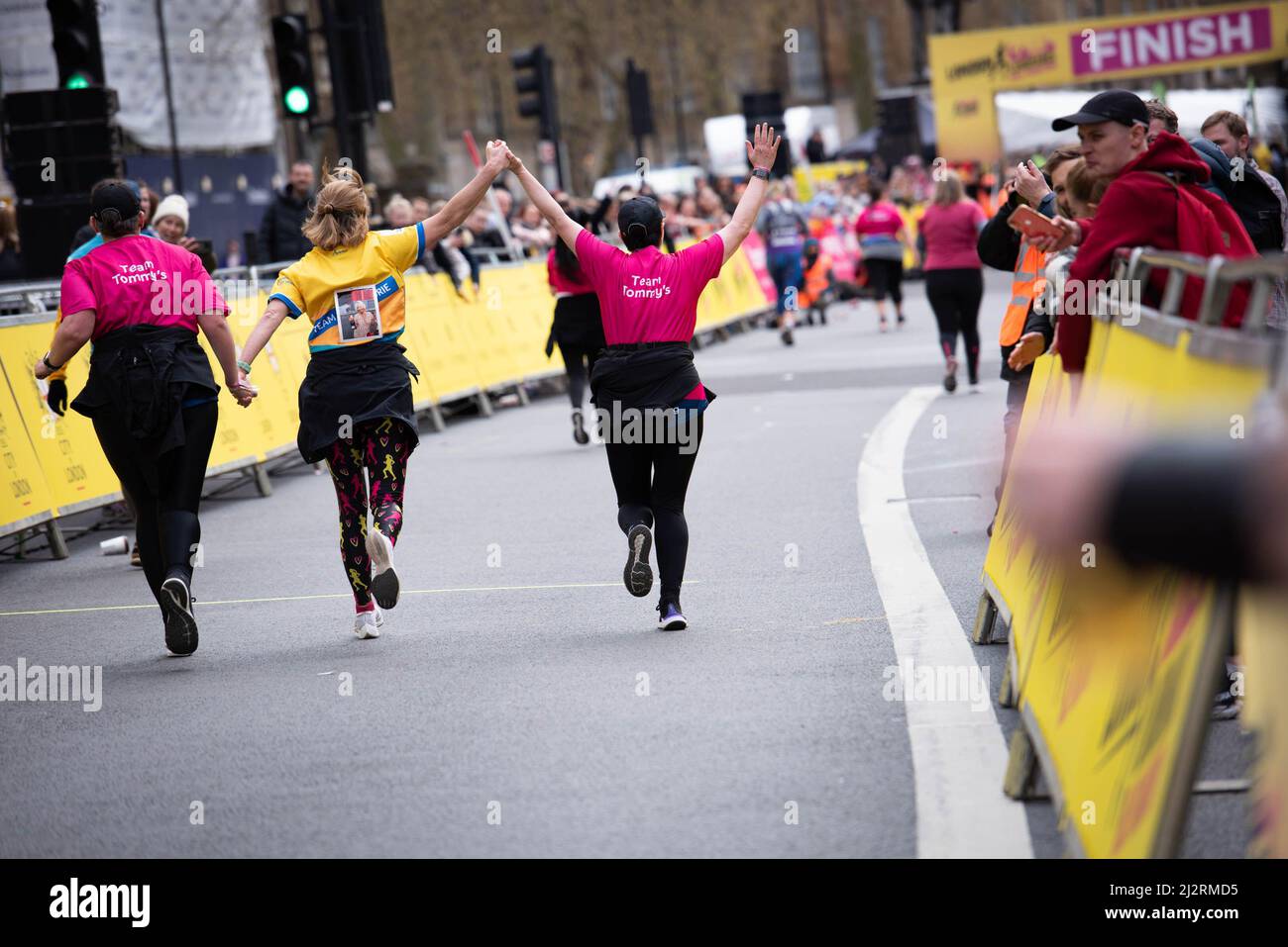 Runners hold hands as they approach the finish line during the London ...
