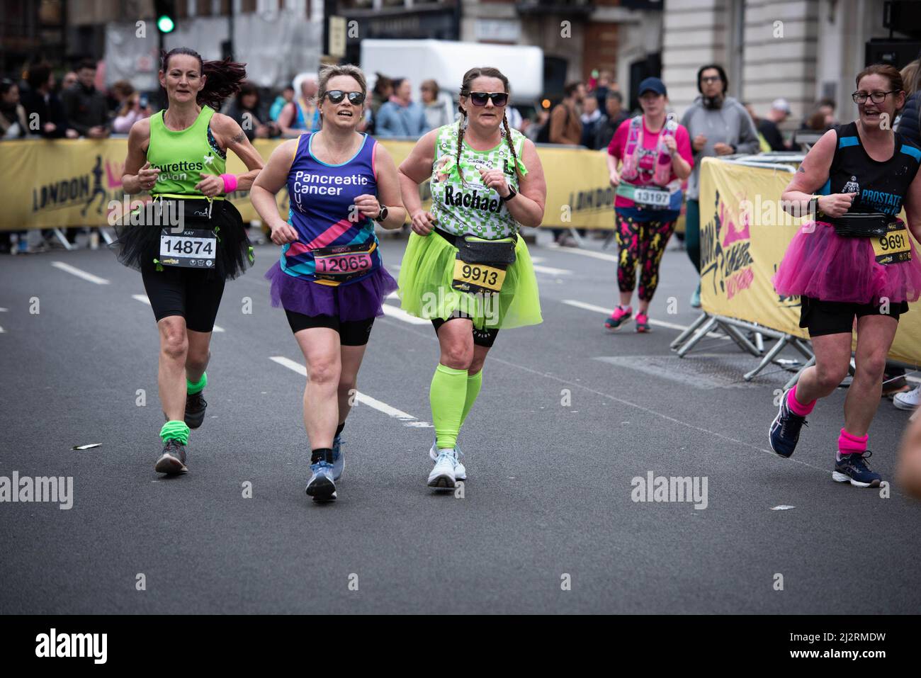 Runners dressed in tutus approach the finish line during the London ...