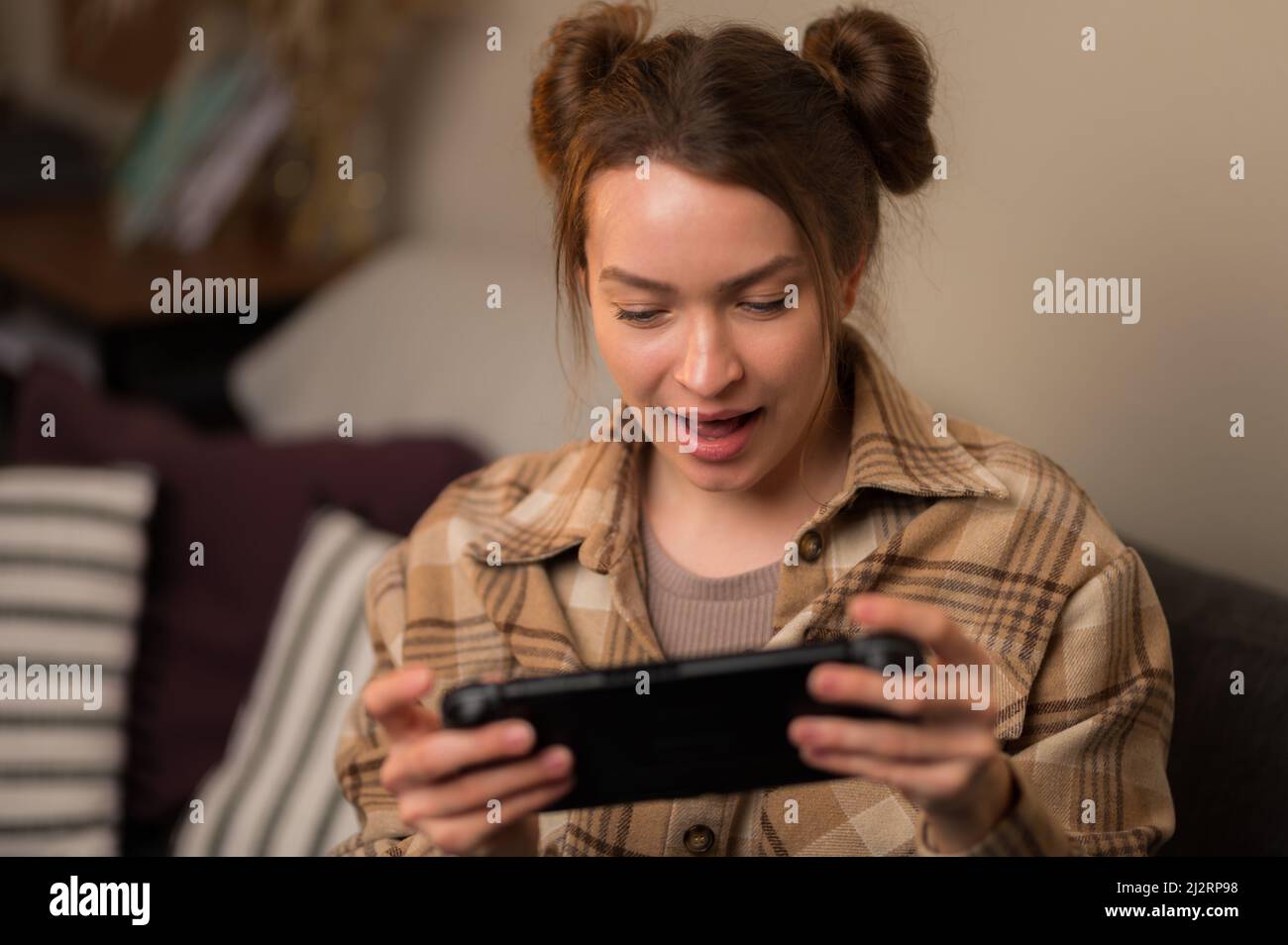 A girl gamer plays a video game on a mobile portable game console in ...