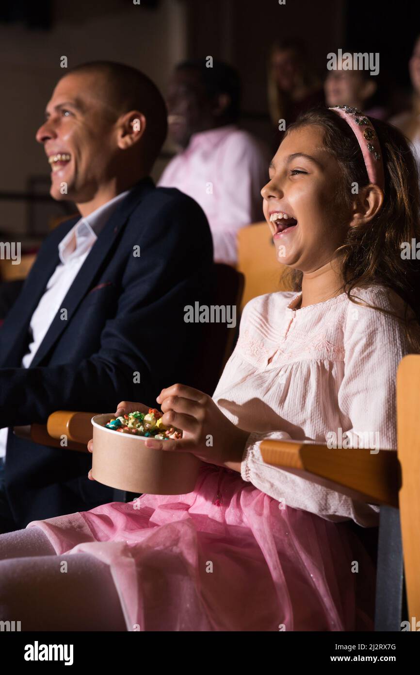 Tween girl laughing while watching comedy at movie theater Stock Photo ...