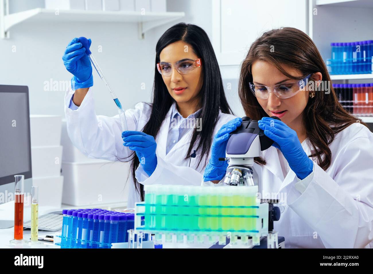 Two beautiful young female scientists working in laboratory with test ...