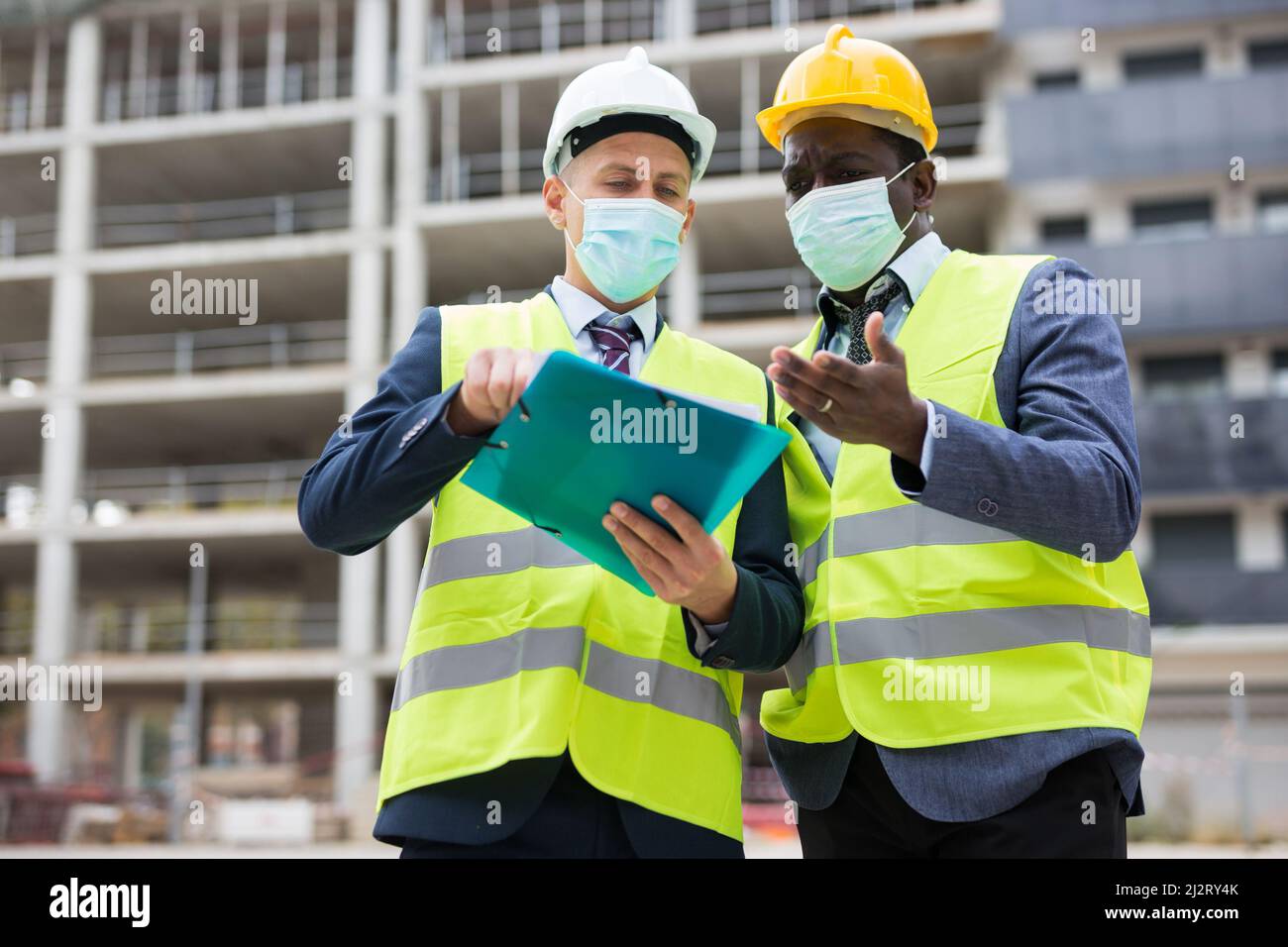 Engineers in masks standing on construction site Stock Photo - Alamy