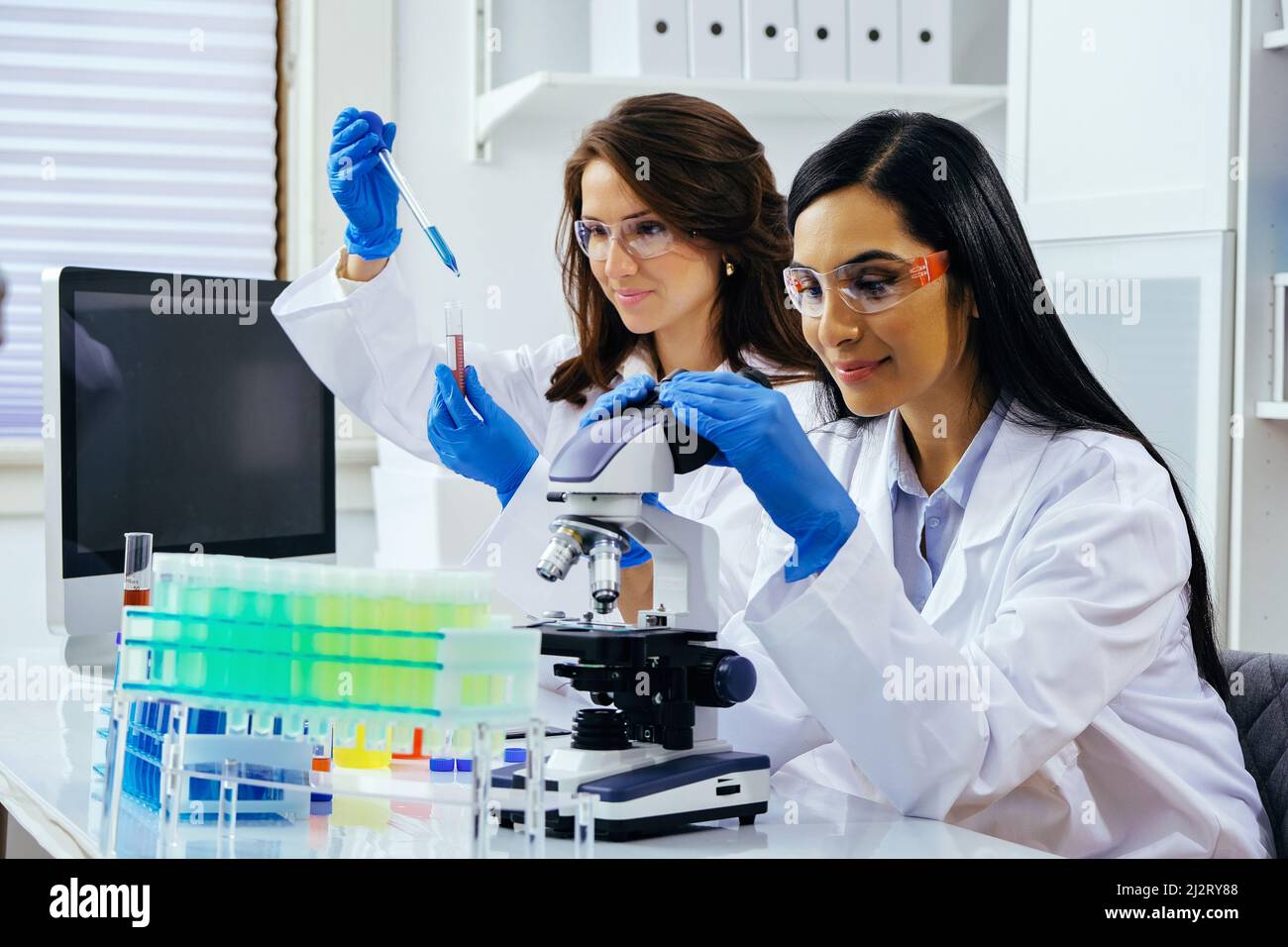 Two beautiful young female scientists working in laboratory with test ...