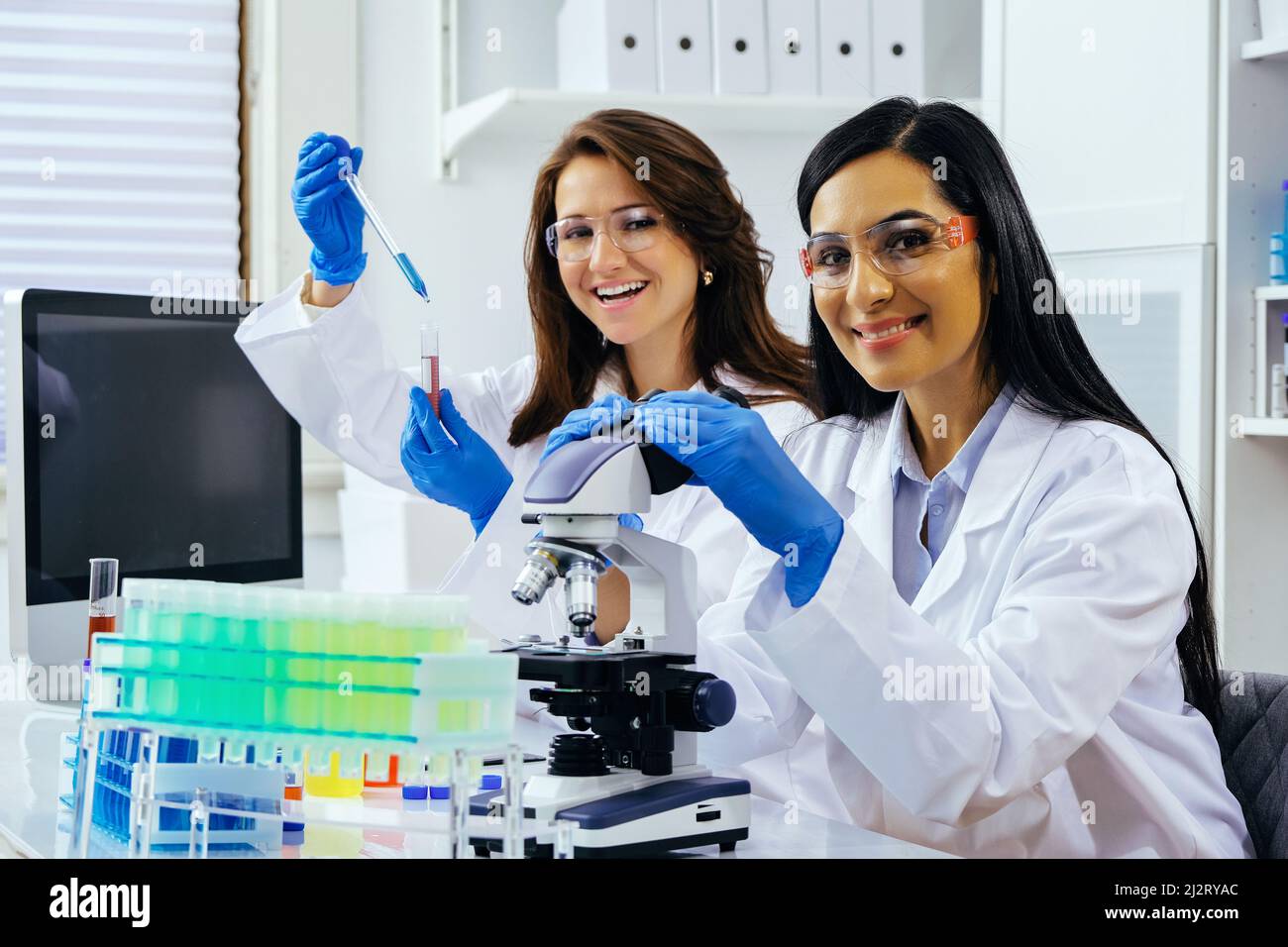 Two beautiful young female scientists working in laboratory with test ...