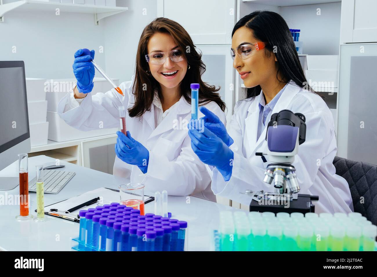 Two beautiful young female scientists working in laboratory with test ...