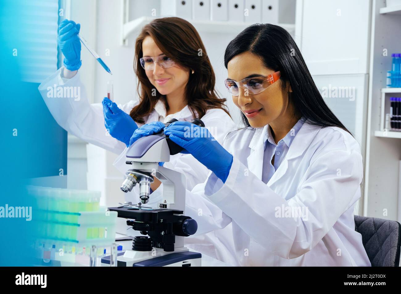 Two beautiful young female scientists working in laboratory with test ...