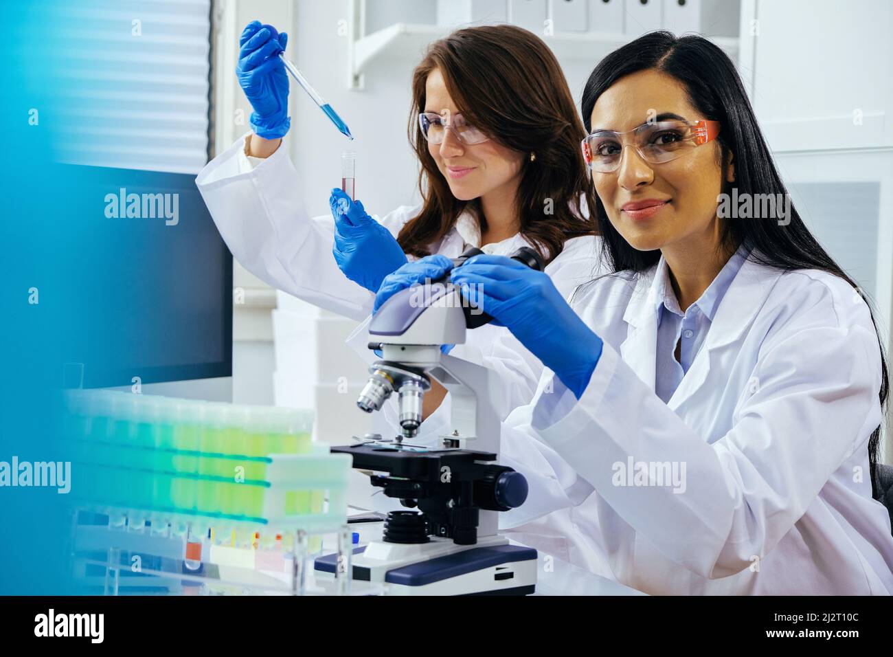 Two beautiful young female scientists working in laboratory with test ...