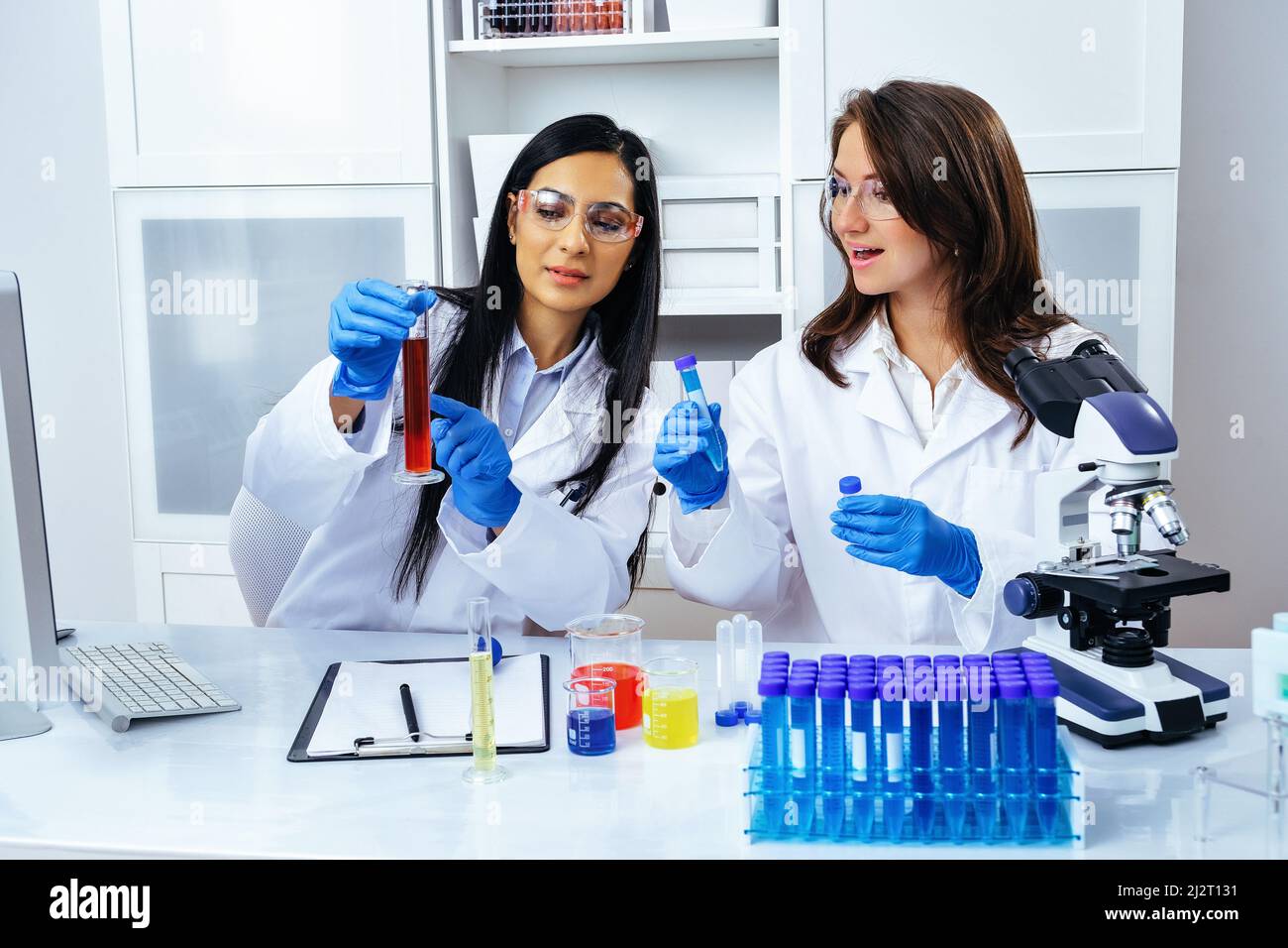 Two beautiful young female scientists working in laboratory with test ...