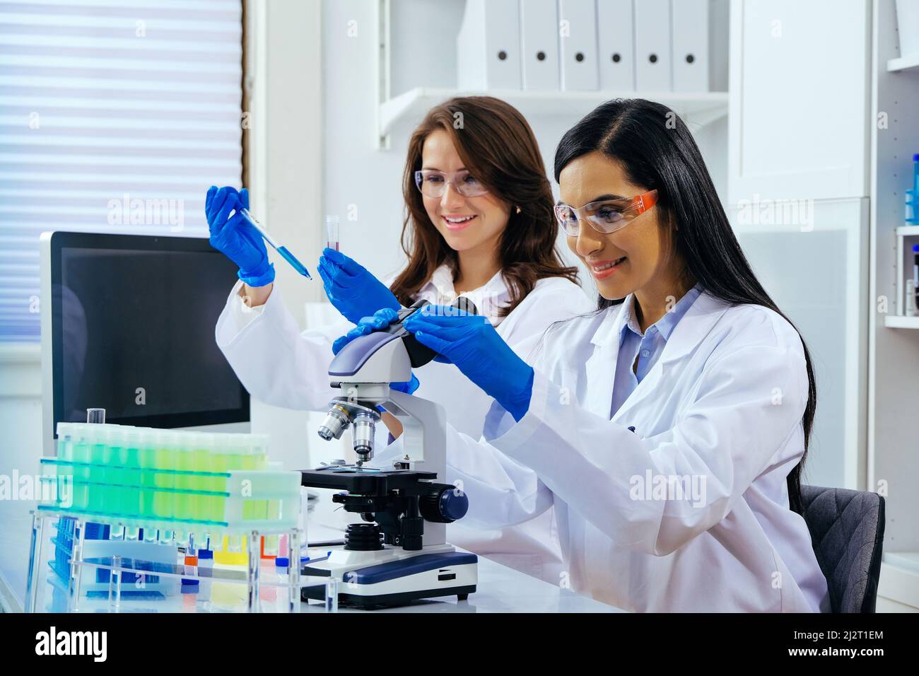 Two beautiful young female scientists working in laboratory with test ...