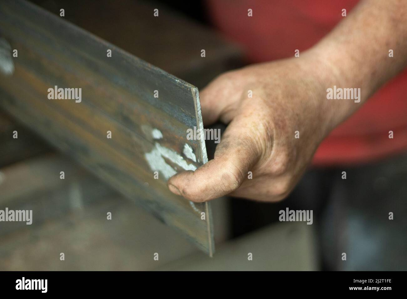 Worker with metal. The guy holds a steel part. Hard work in a ...