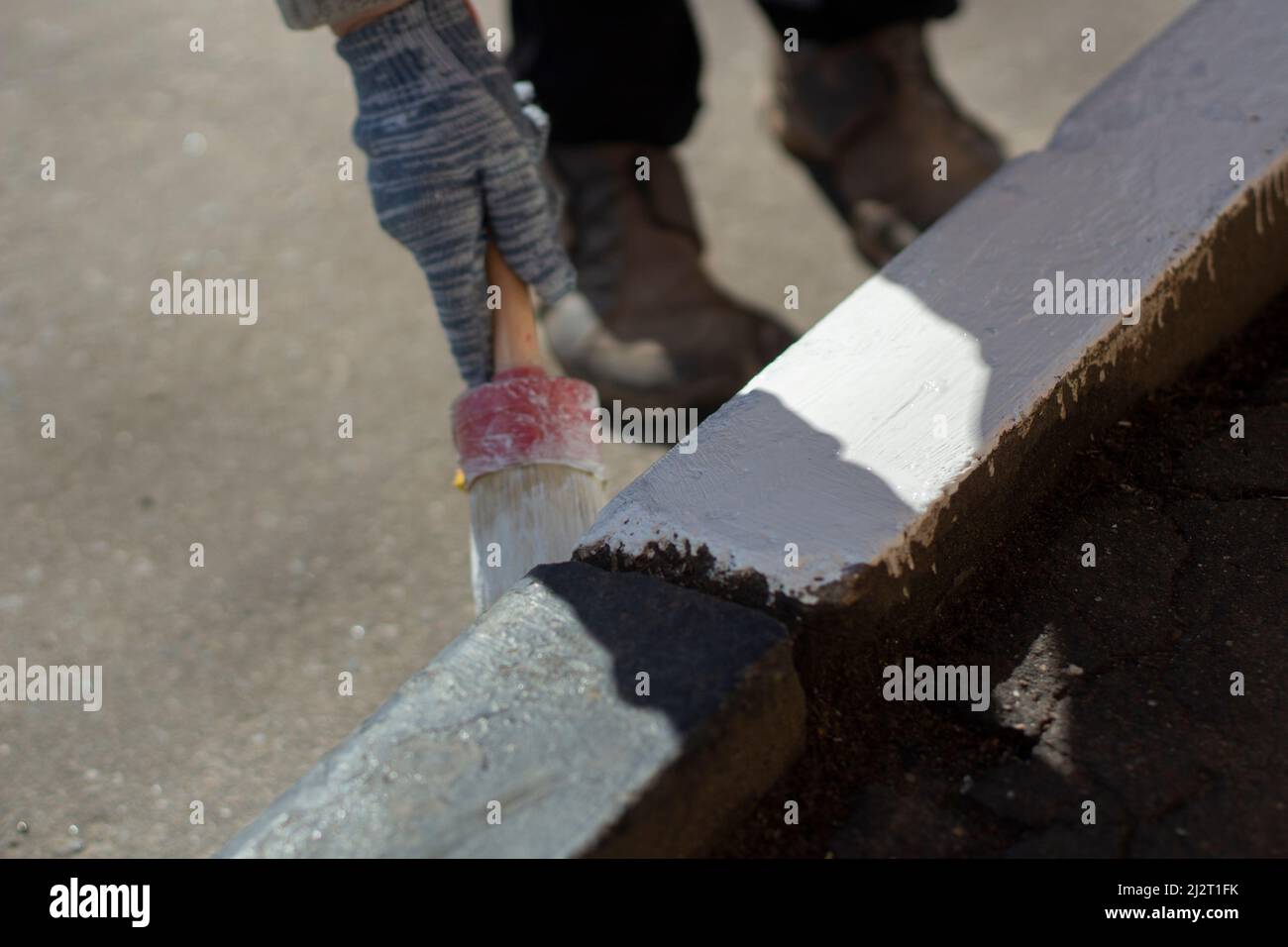 Paints the kerb with white paint. Brush with paint for the road curb ...
