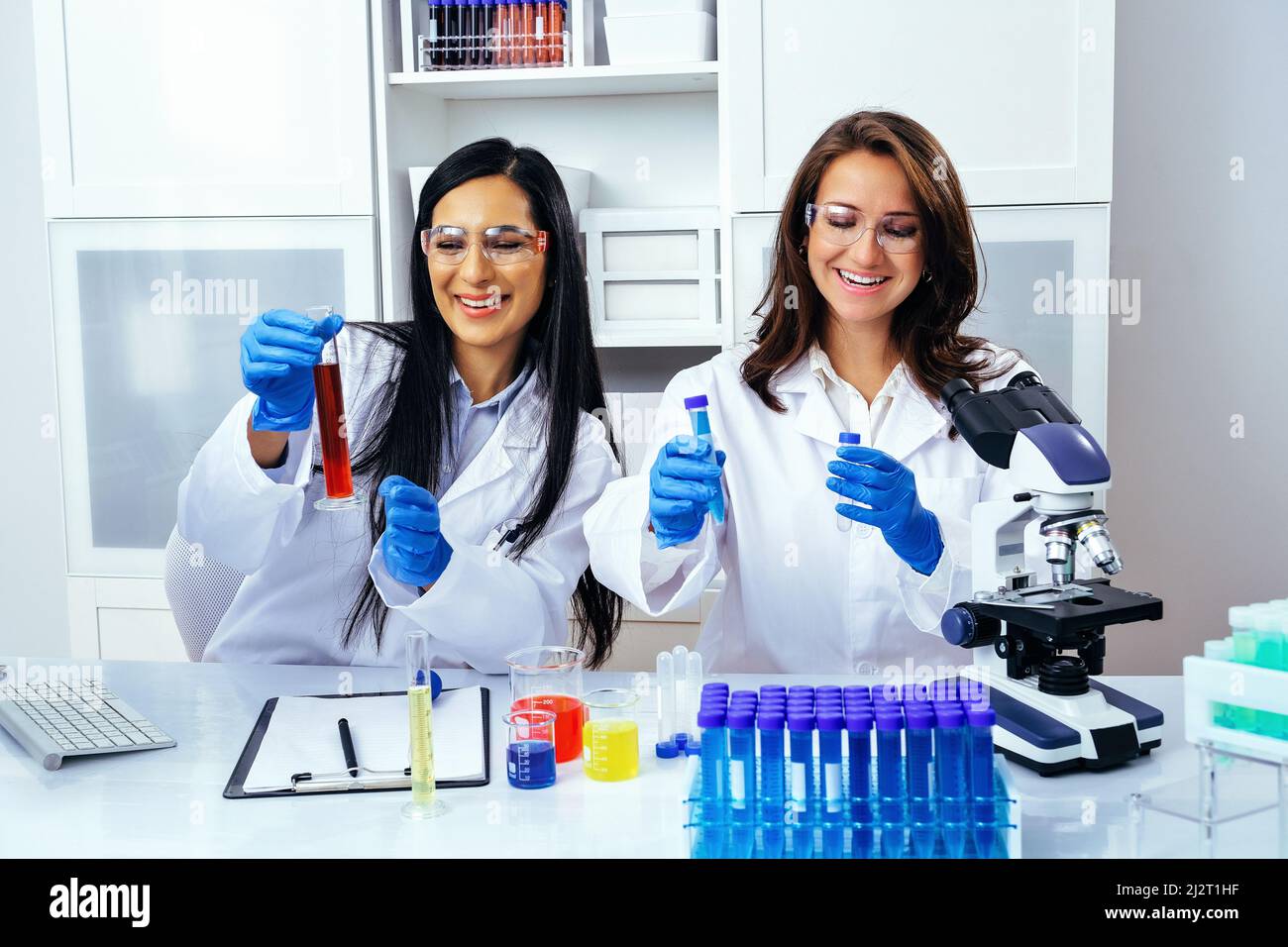 Two beautiful young female scientists working in laboratory with test ...