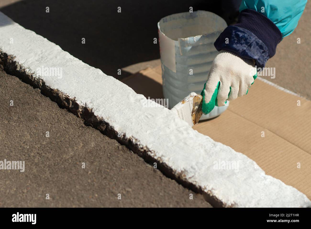 Painting borders with white paint. Applying oil paint to asphalt ...