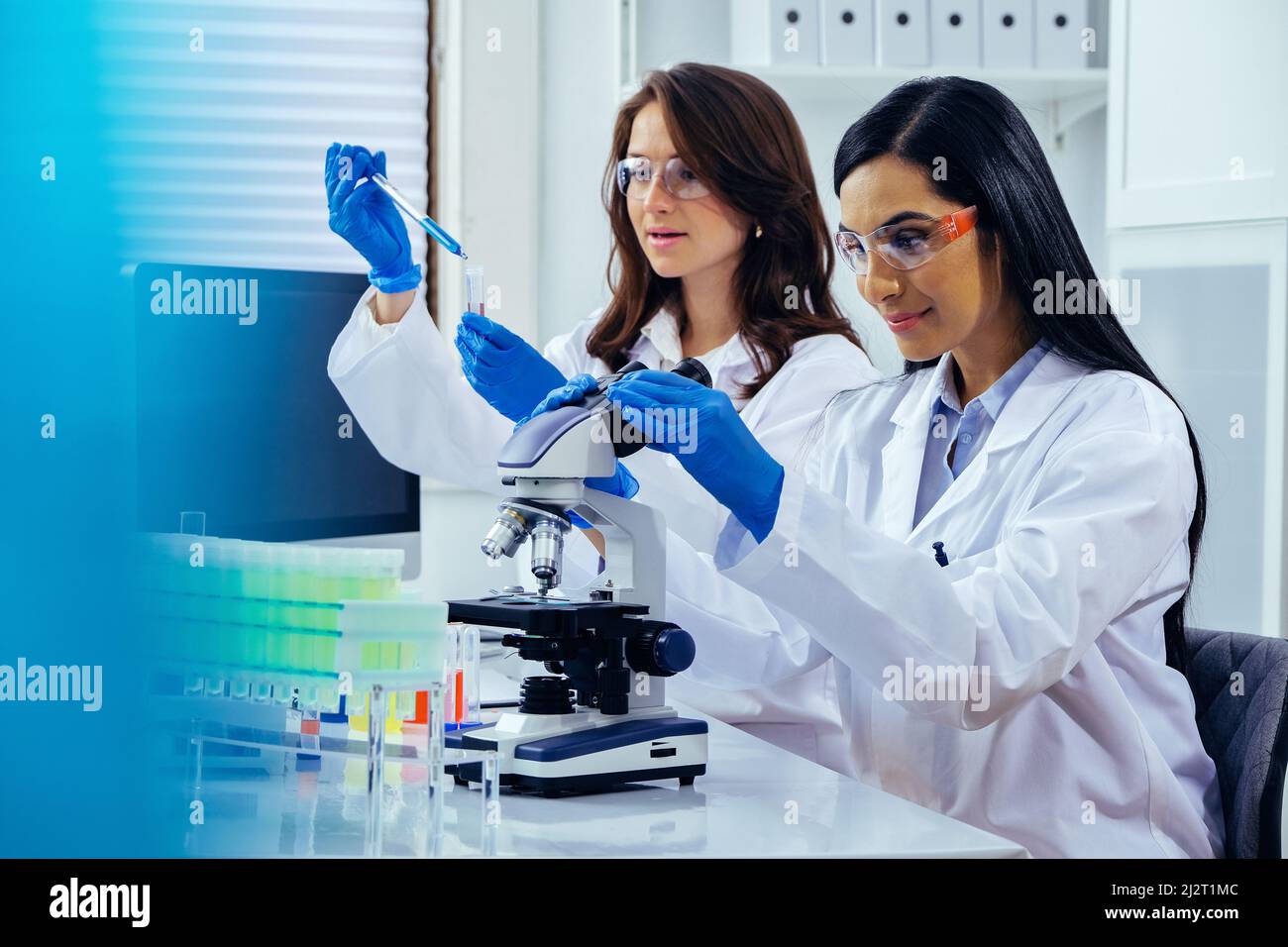 Two beautiful young female scientists working in laboratory with test ...