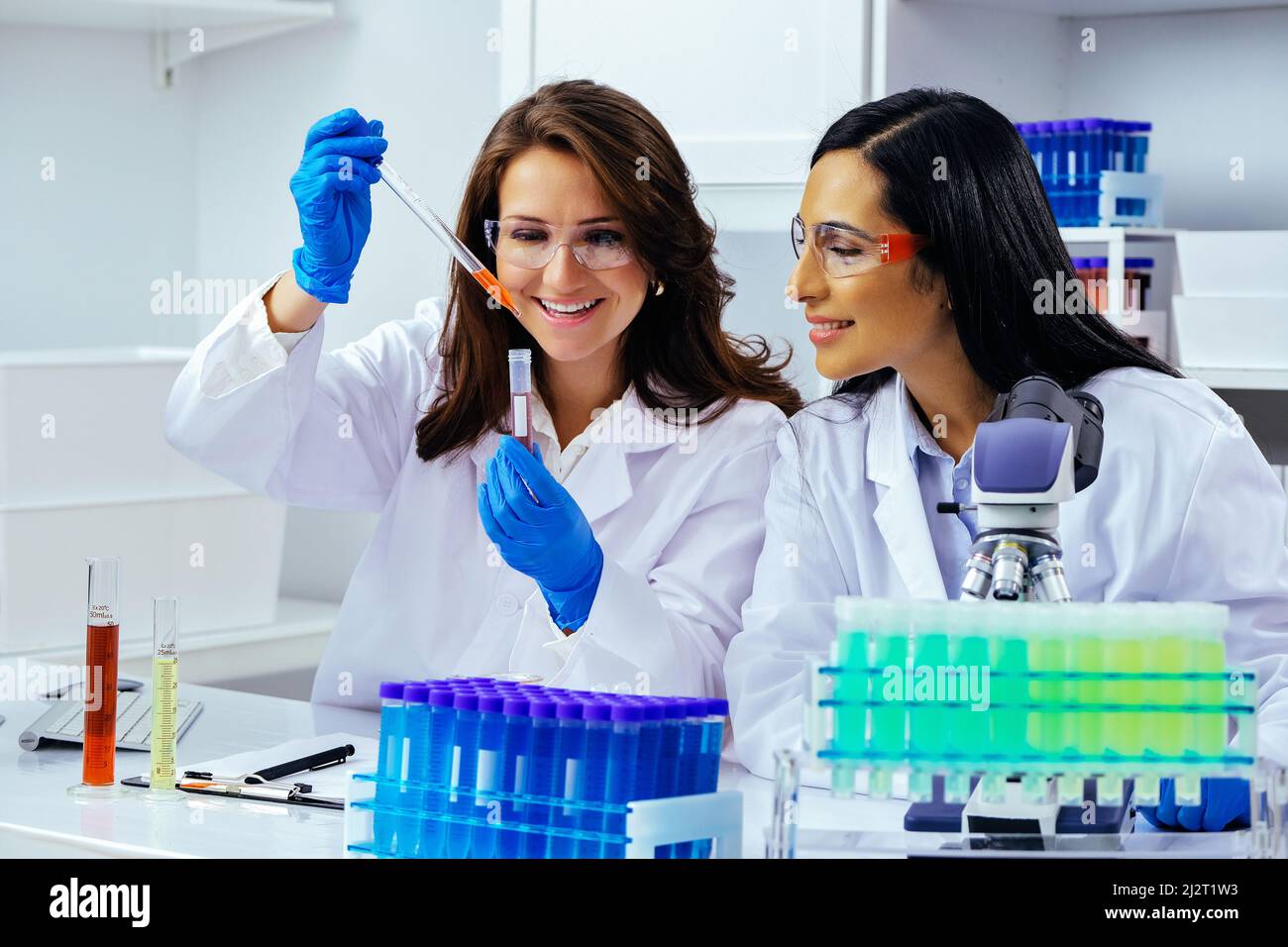 Two beautiful young female scientists working in laboratory with test ...