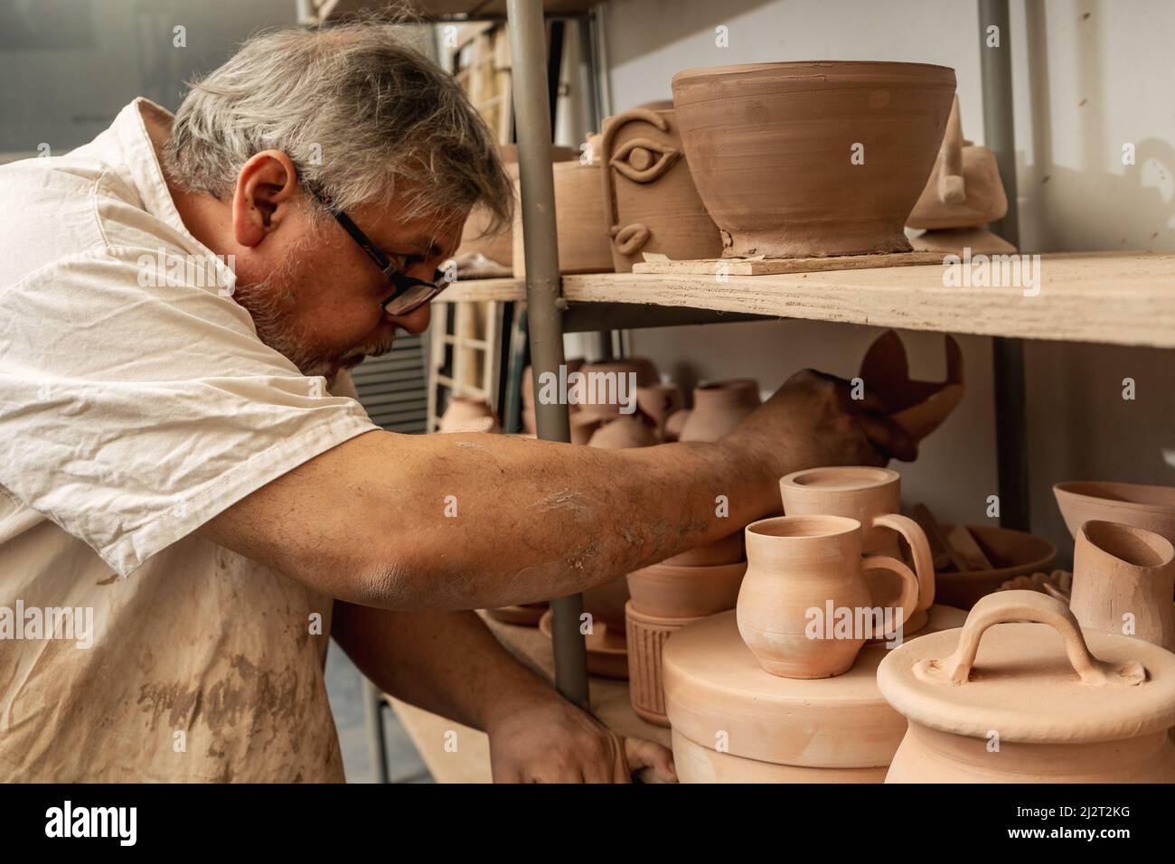 Pottery craftsman checking the pieces and organizing the shelves. Clay ...