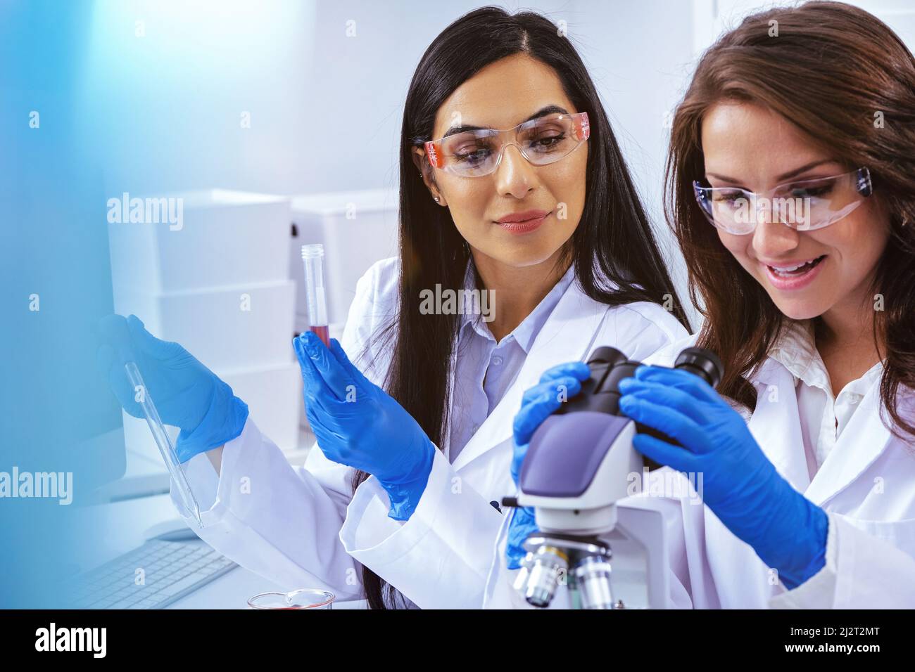 Two beautiful young female scientists working in laboratory with test ...
