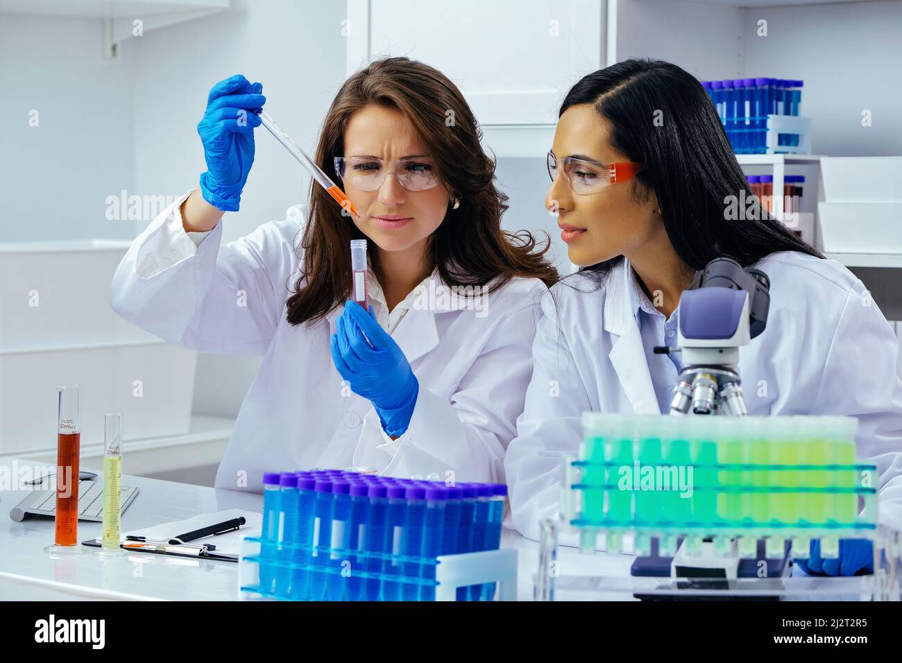 Two beautiful young female scientists working in laboratory with test ...