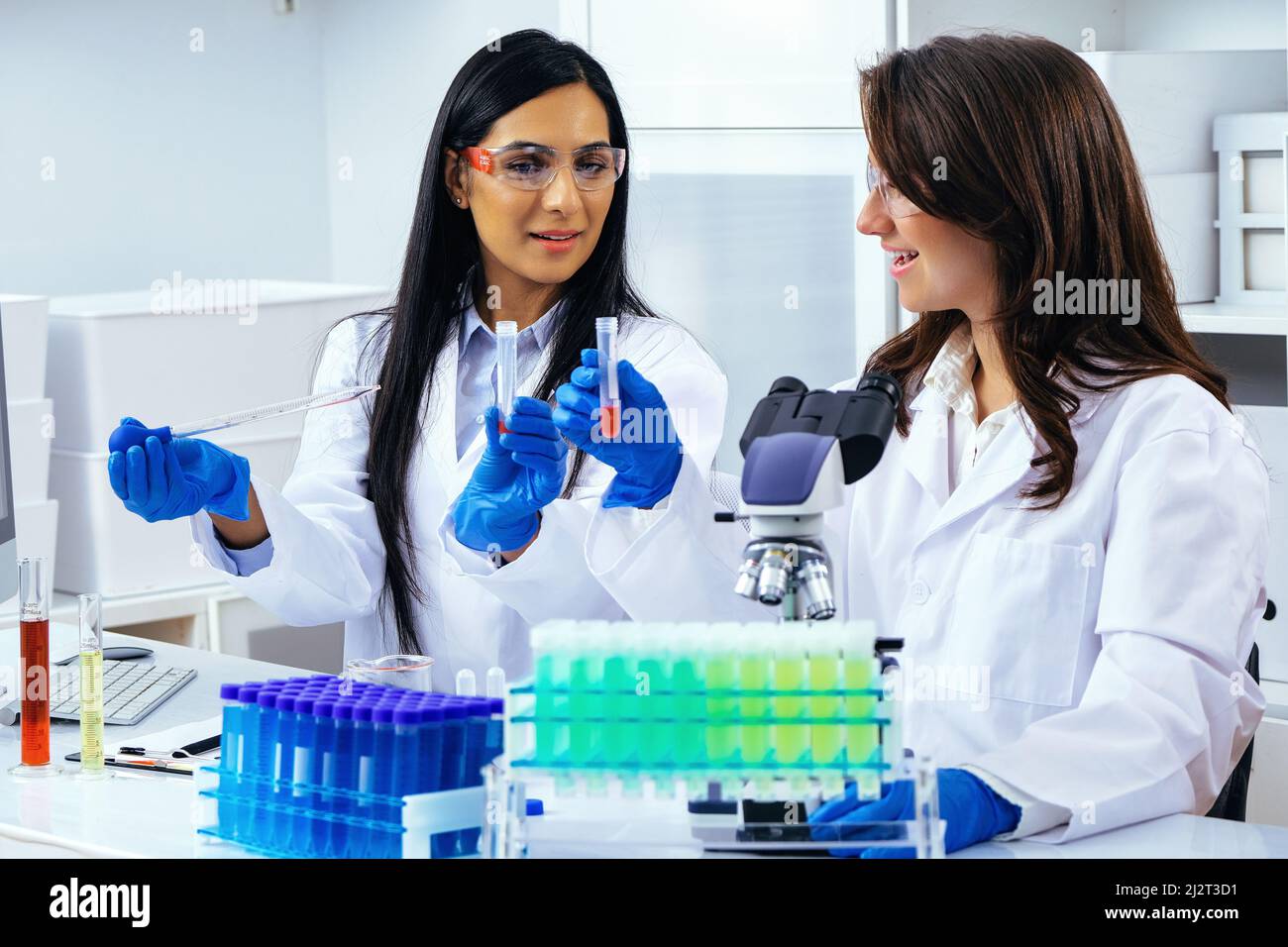 Two beautiful young female scientists working in laboratory with test ...