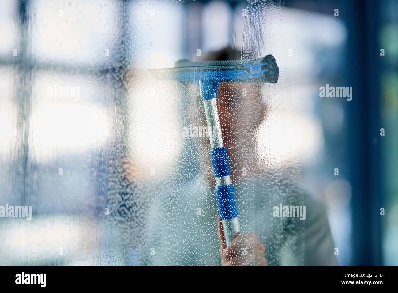 Clean and hygienic. Shot of a young man cleaning the windows in the ...