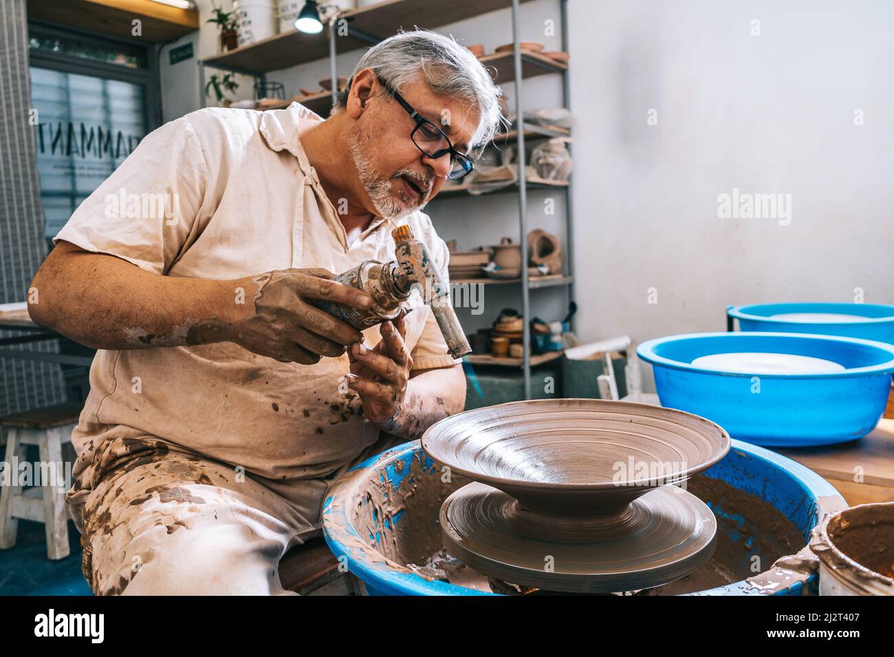 A skilled potter drying the piece formed on the potter's wheel with a ...