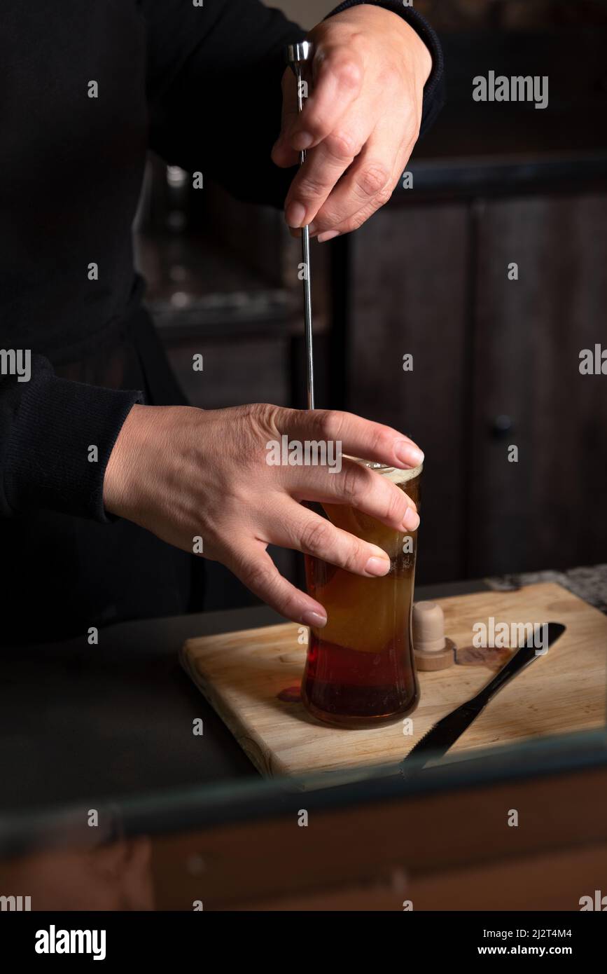 PREPARATION OF ALCOHOLIC BEVERAGE. VERTICAL PHOTOGRAPH, DARK BACKGROUND ...