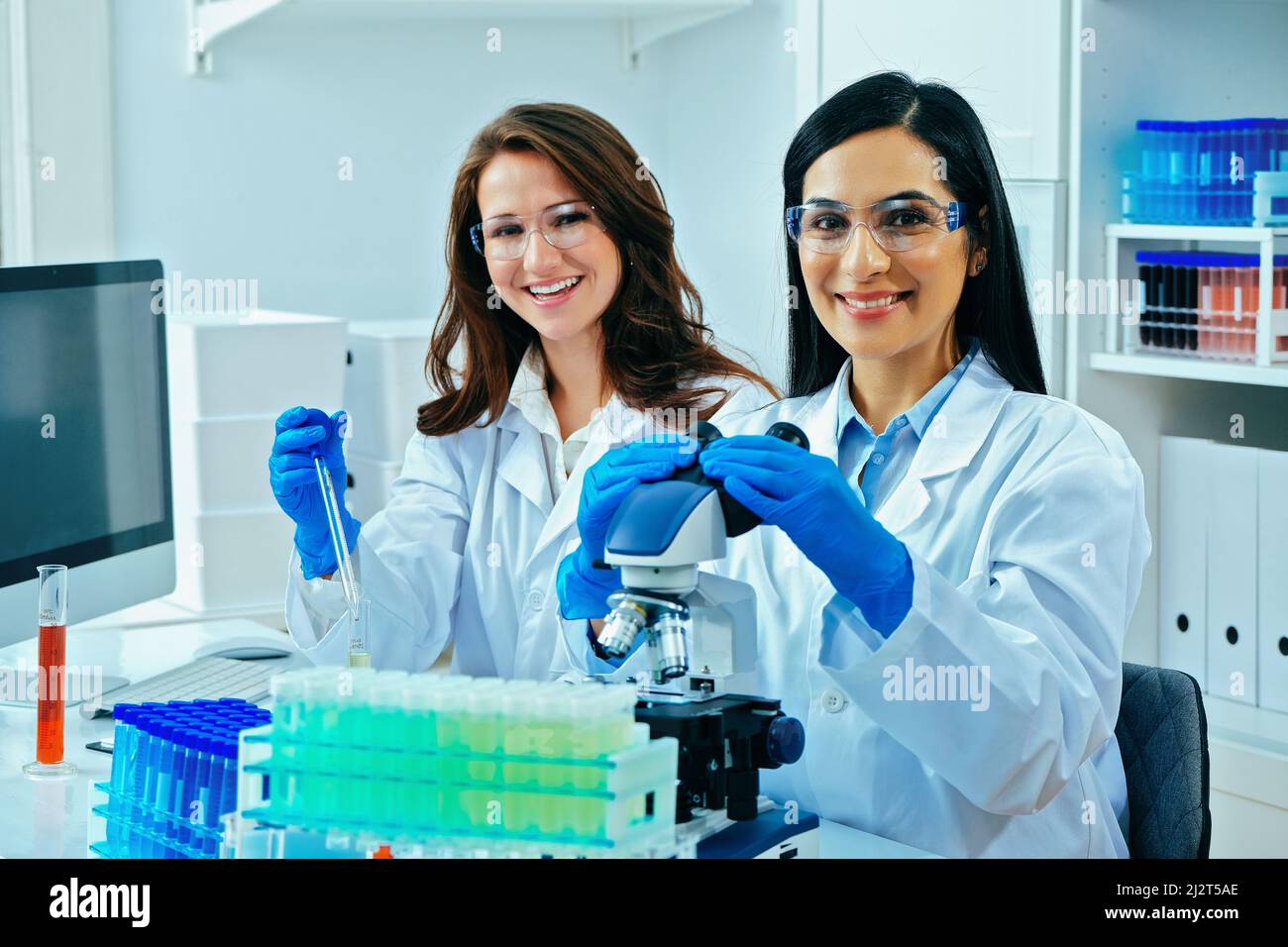 Two beautiful young female scientists working in laboratory with test ...