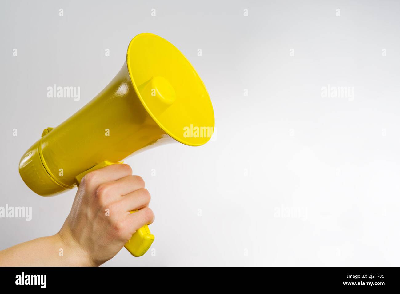 A man's hand is holding a yellow megaphone. Isolated on white ...
