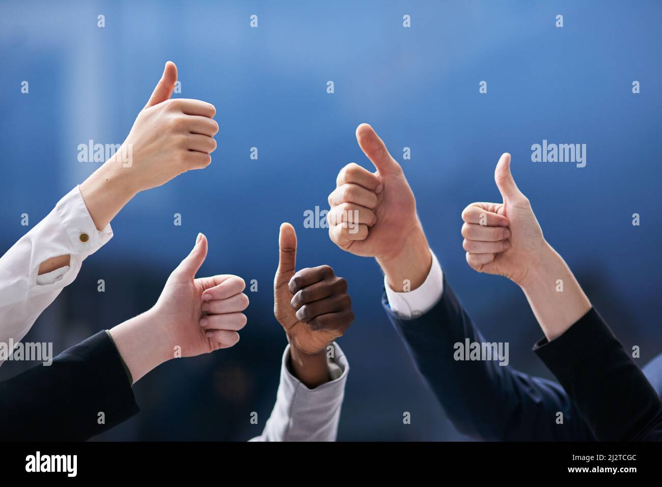 Teamwork trumps all. Shot of a group of office workers giving thumbs up ...