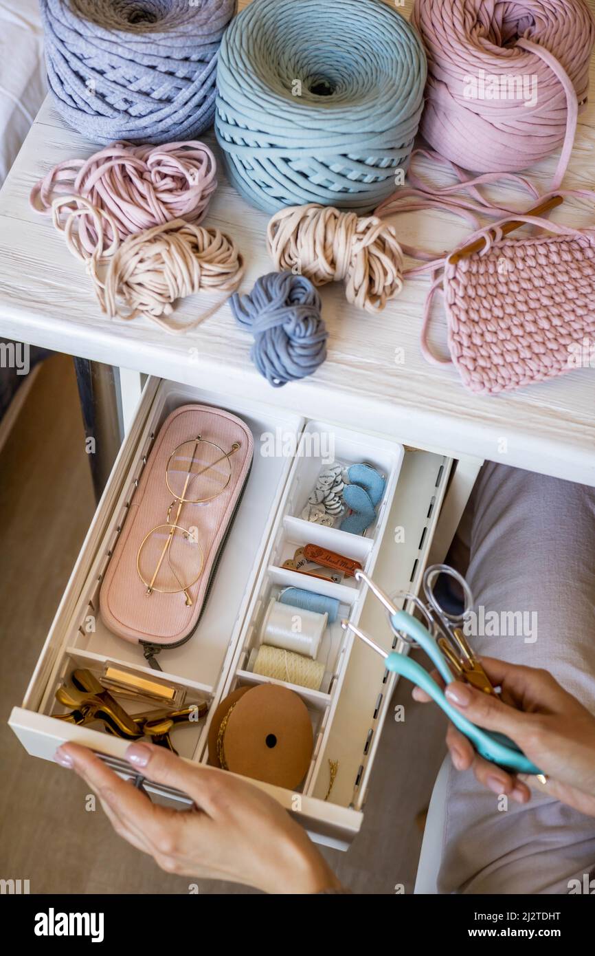 Female hands putting scissors into drawer with sewing accessories ...