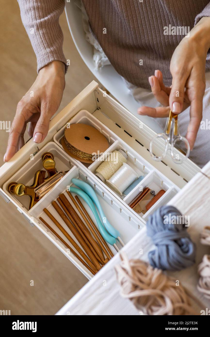 Female hands putting scissors into drawer with sewing accessories ...