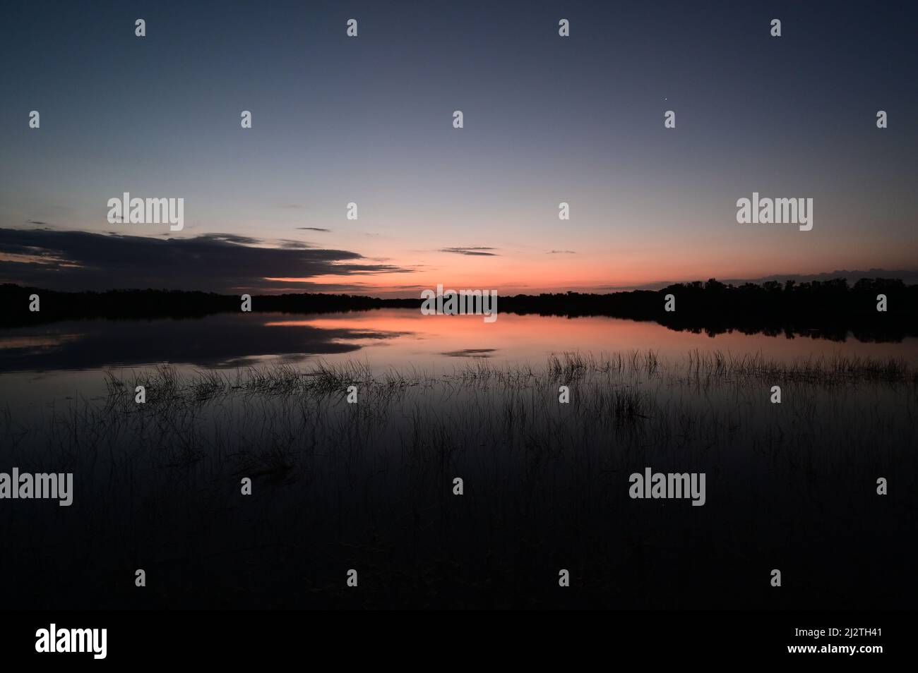 Colorful sunrise reflected in the calm water of Nine Mile Pond in ...