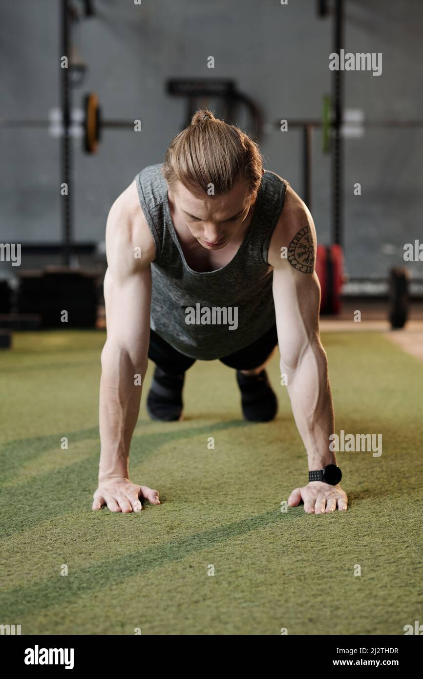 Strong fit young man doing push-ups on gym floor to warm-up before ...