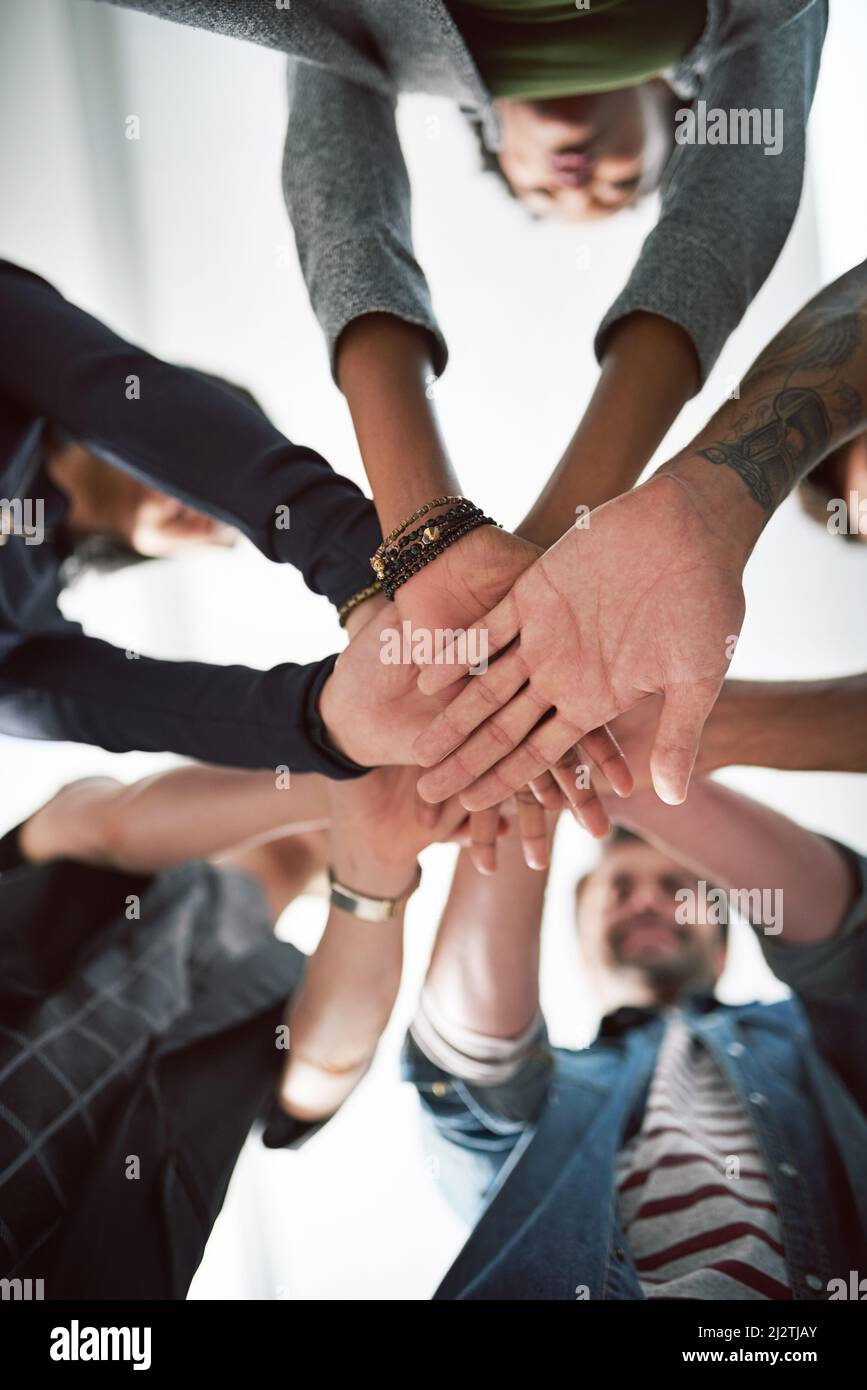 Many hands make light work. Cropped shot of a group of people stacking ...