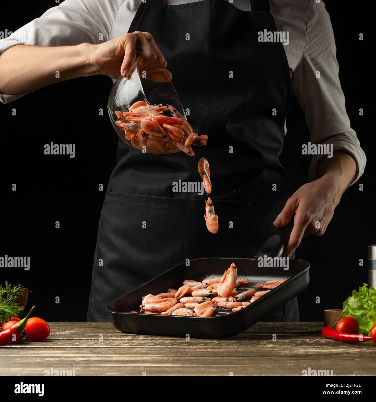 Professional chef prepares a salad of fresh shrimp, and vegetables on a ...