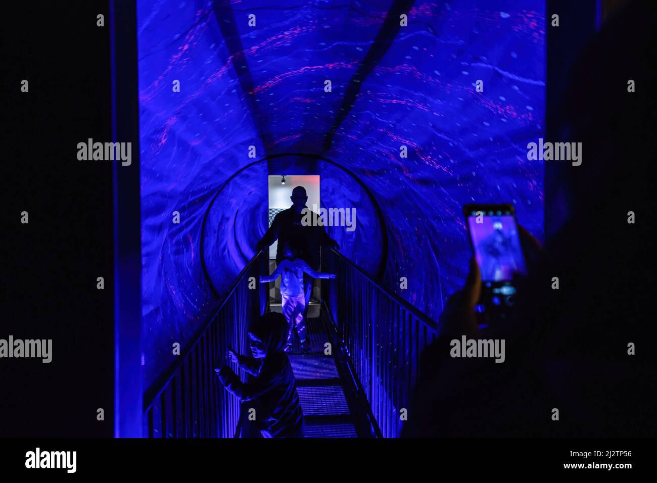 A mother takes a photo as her husband walks on a bridge inside of a ...