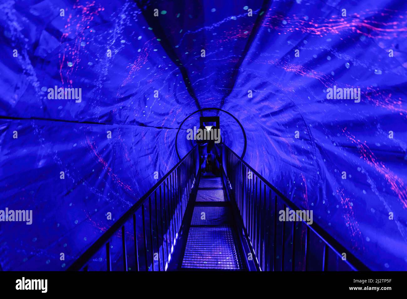 Two young girls walk across a bridge inside of a spinning and ...