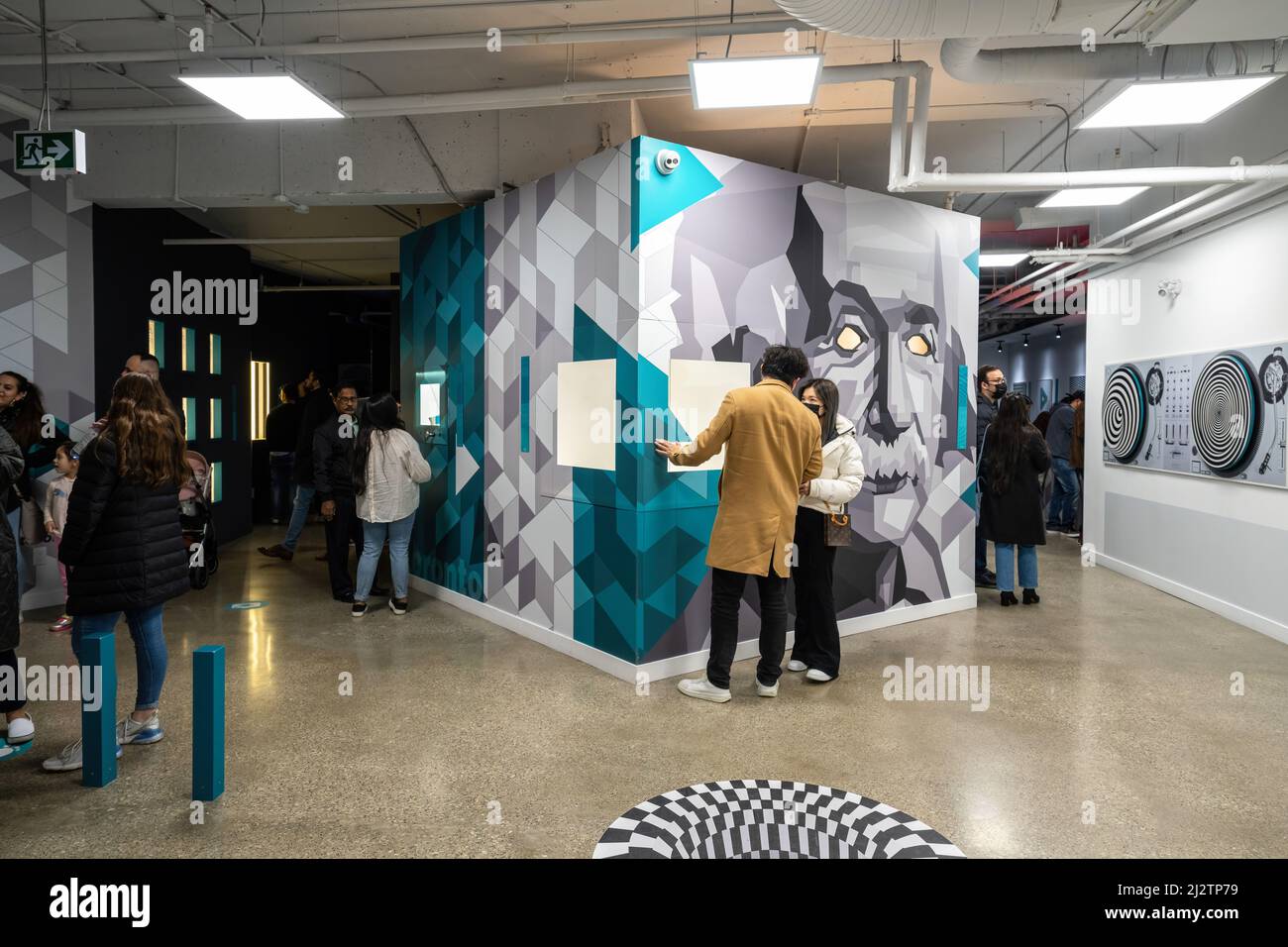 People browse exhibits on a wall featuring the head of Albert Einstein. Visitors view and ...